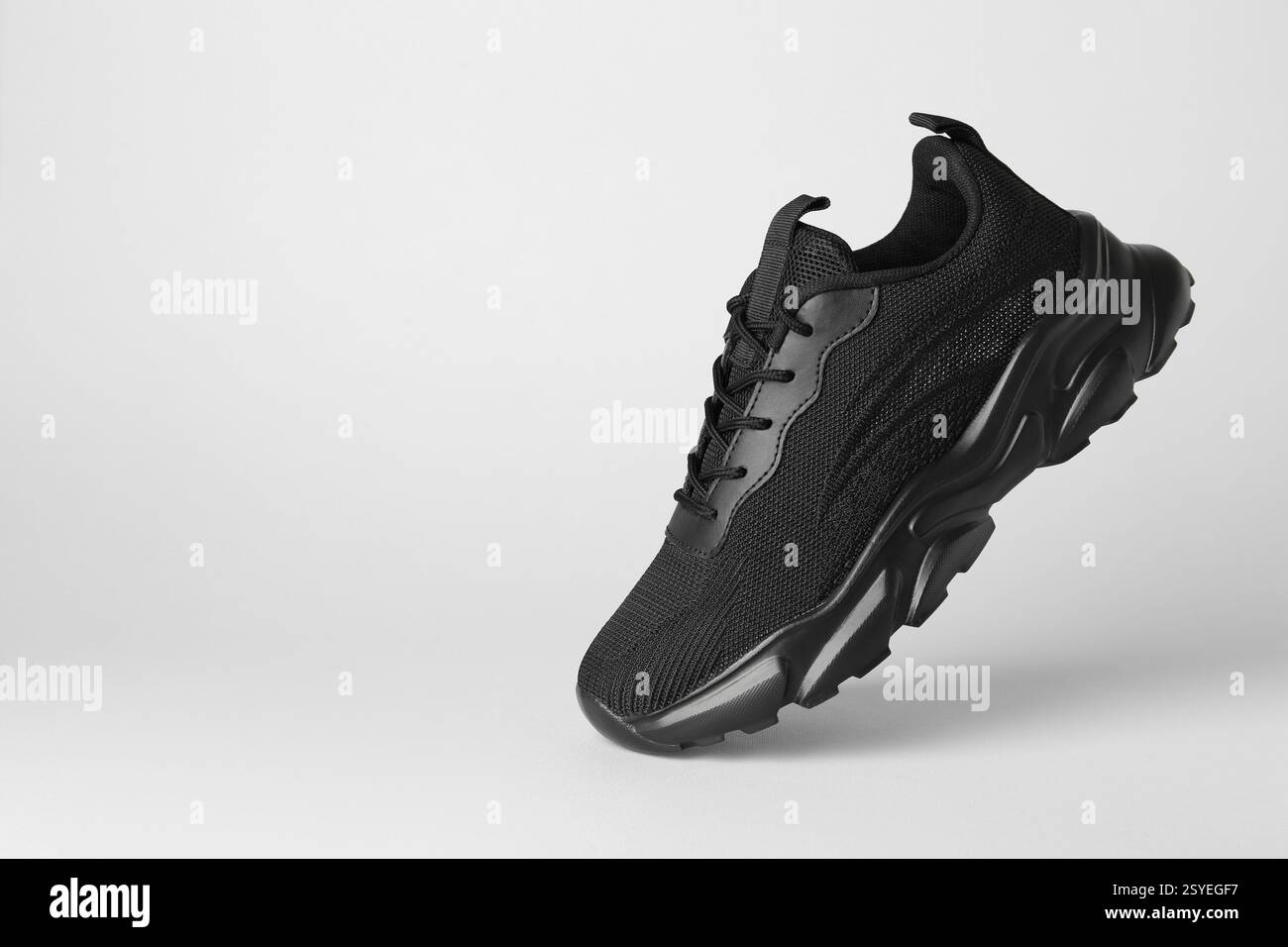 Stylish black sneaker in air against white background Stock Photo - Alamy
