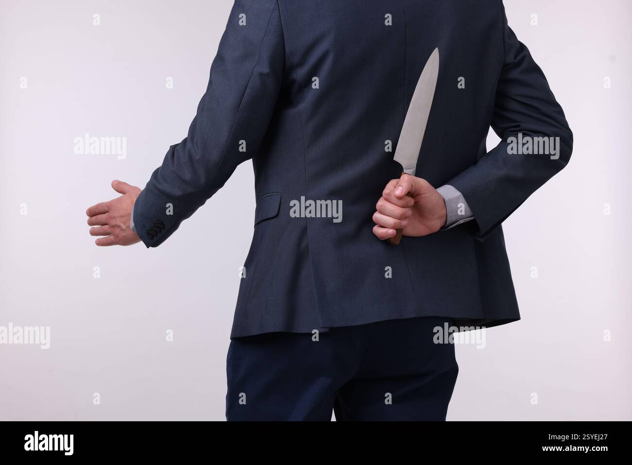 Businessman holding knife behind his back and offering handshake on ...