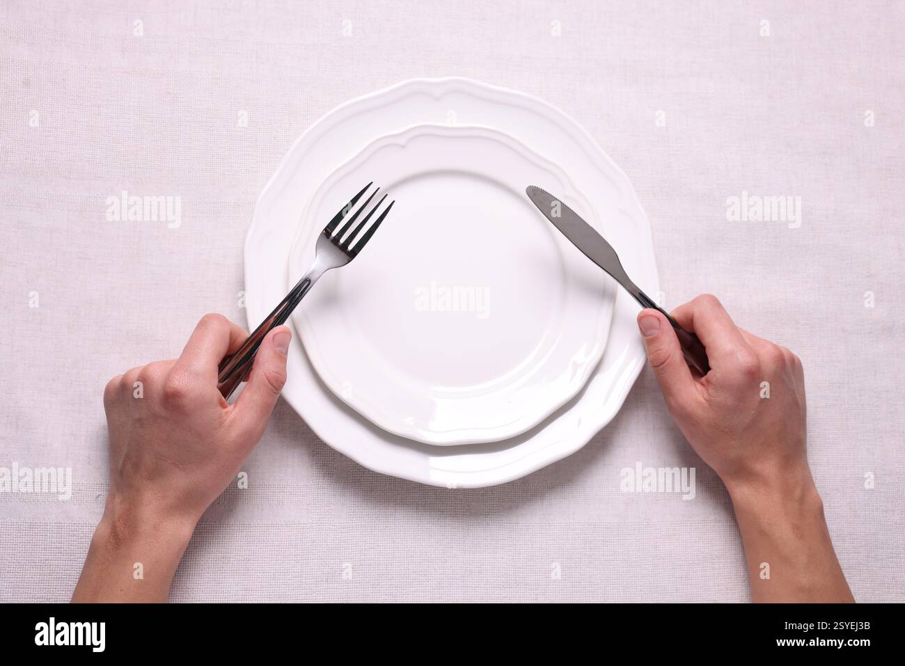 Man with cutlery and clean plates at table, top view Stock Photo - Alamy