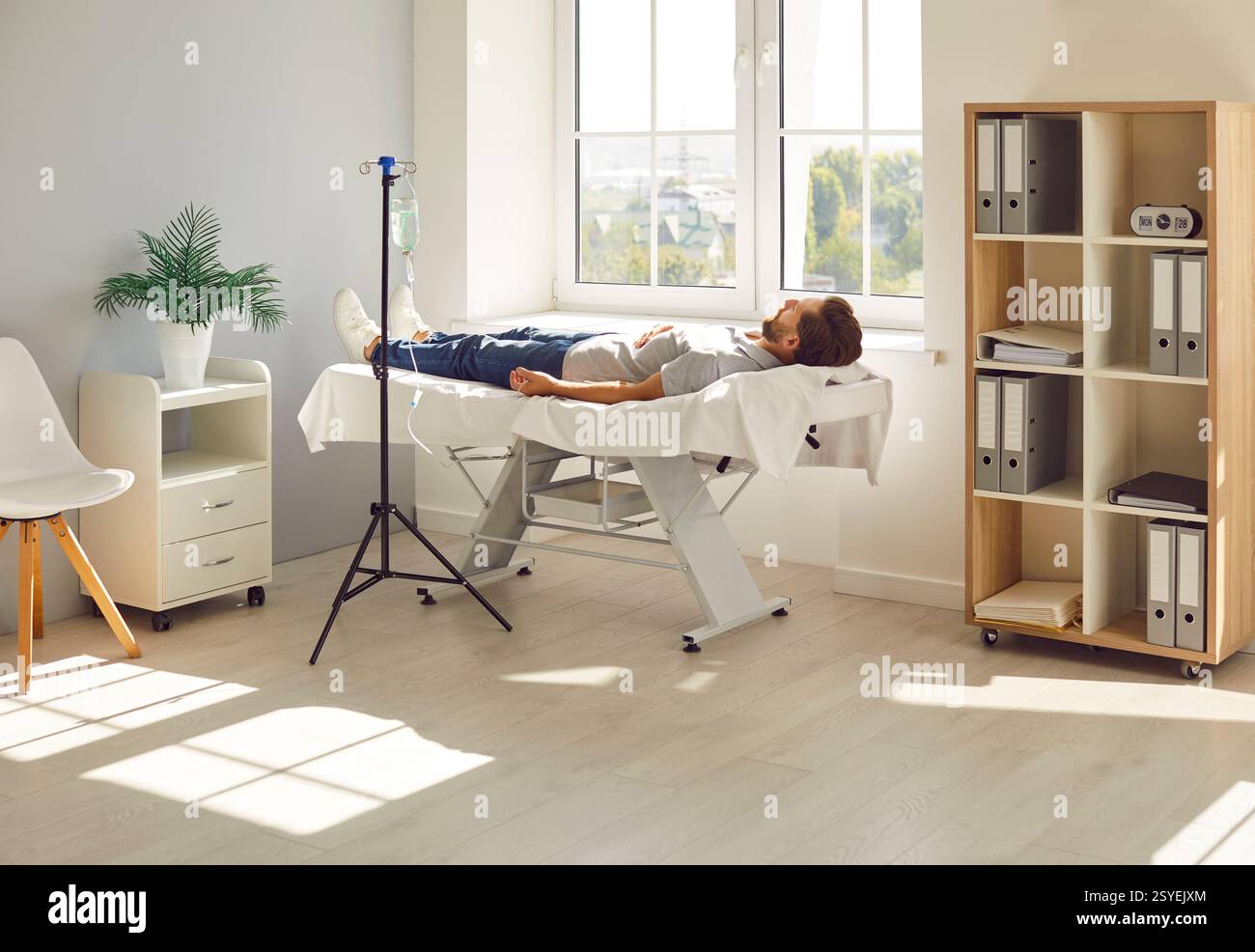 Man lying on the couch in clinic and receiving IV drip infusion and ...