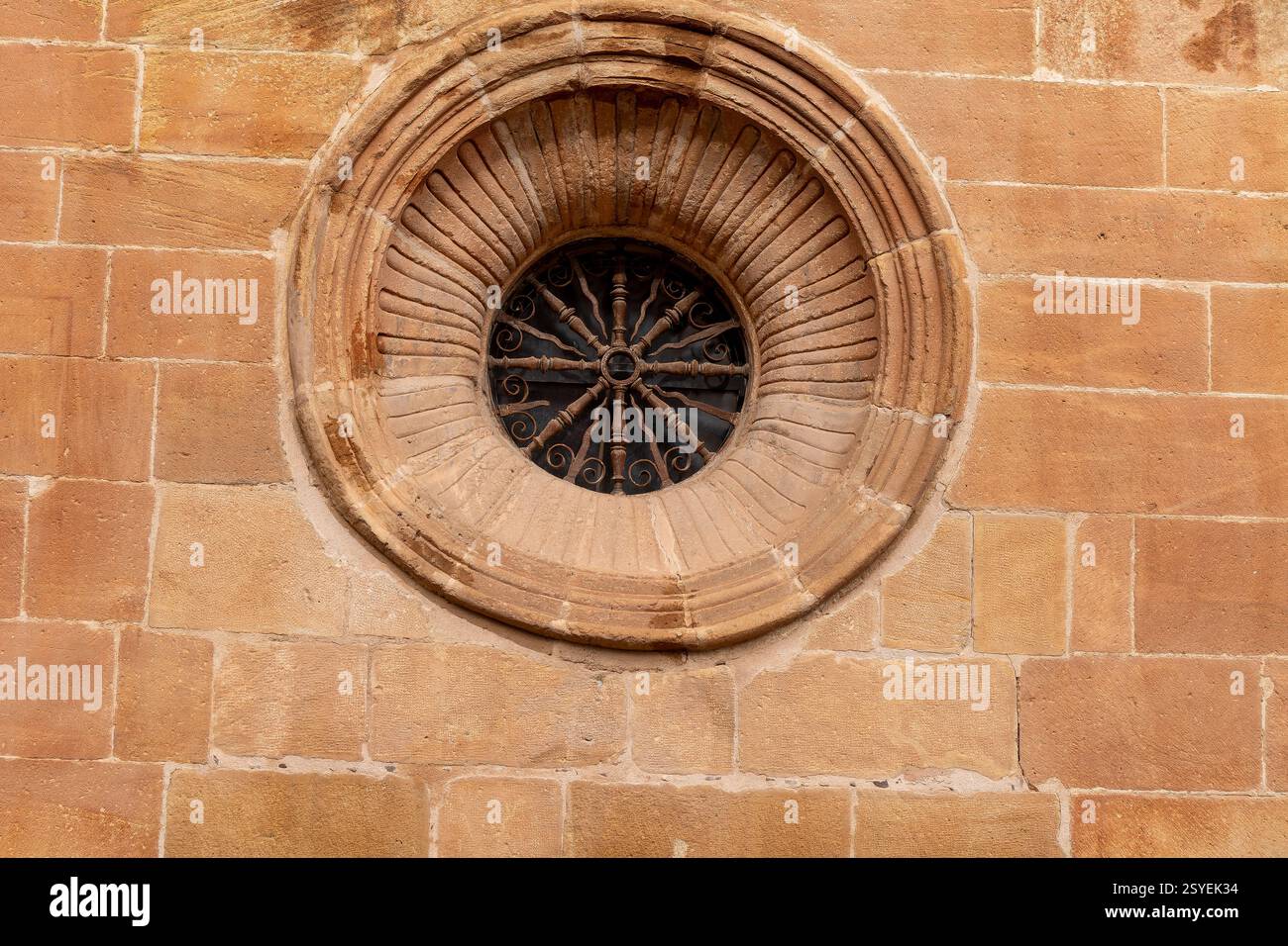 Close-up of a circular stone window with decorative iron grille in the ...
