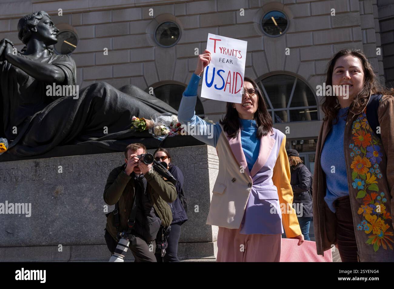 A person holds up a sign saying "Tyrants Fear USAID" after cleaning out ...