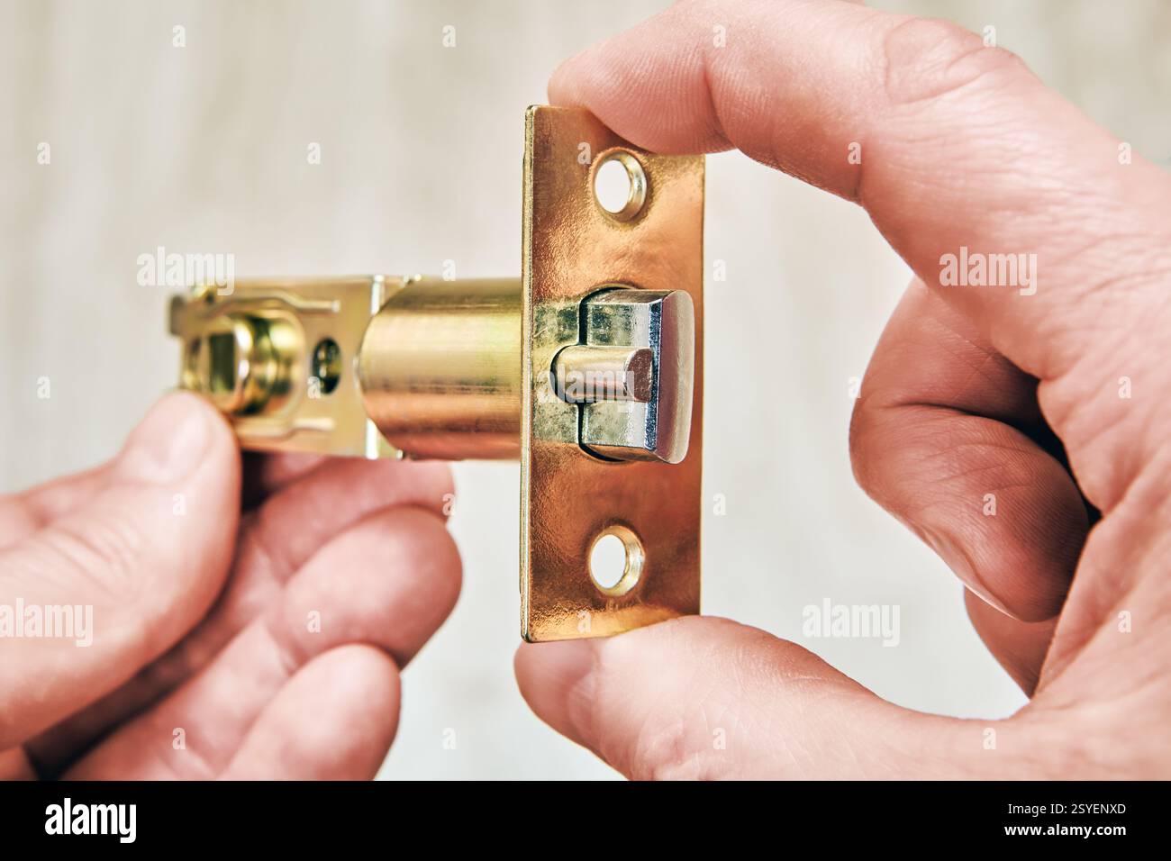 Metal door latch held in fingers for inspection Stock Photo - Alamy