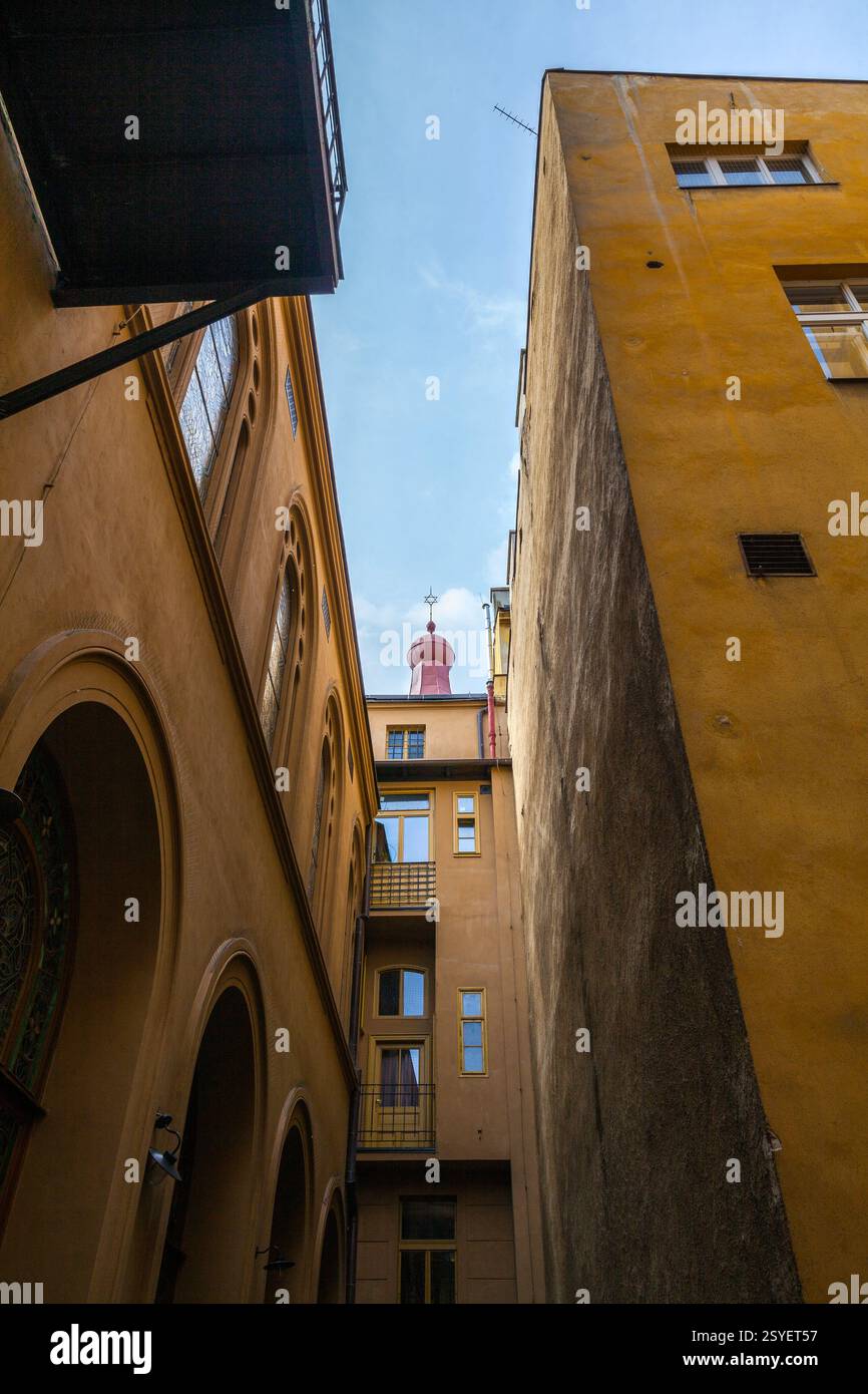 A low-angle shot between two tall buildings, one with arched windows ...