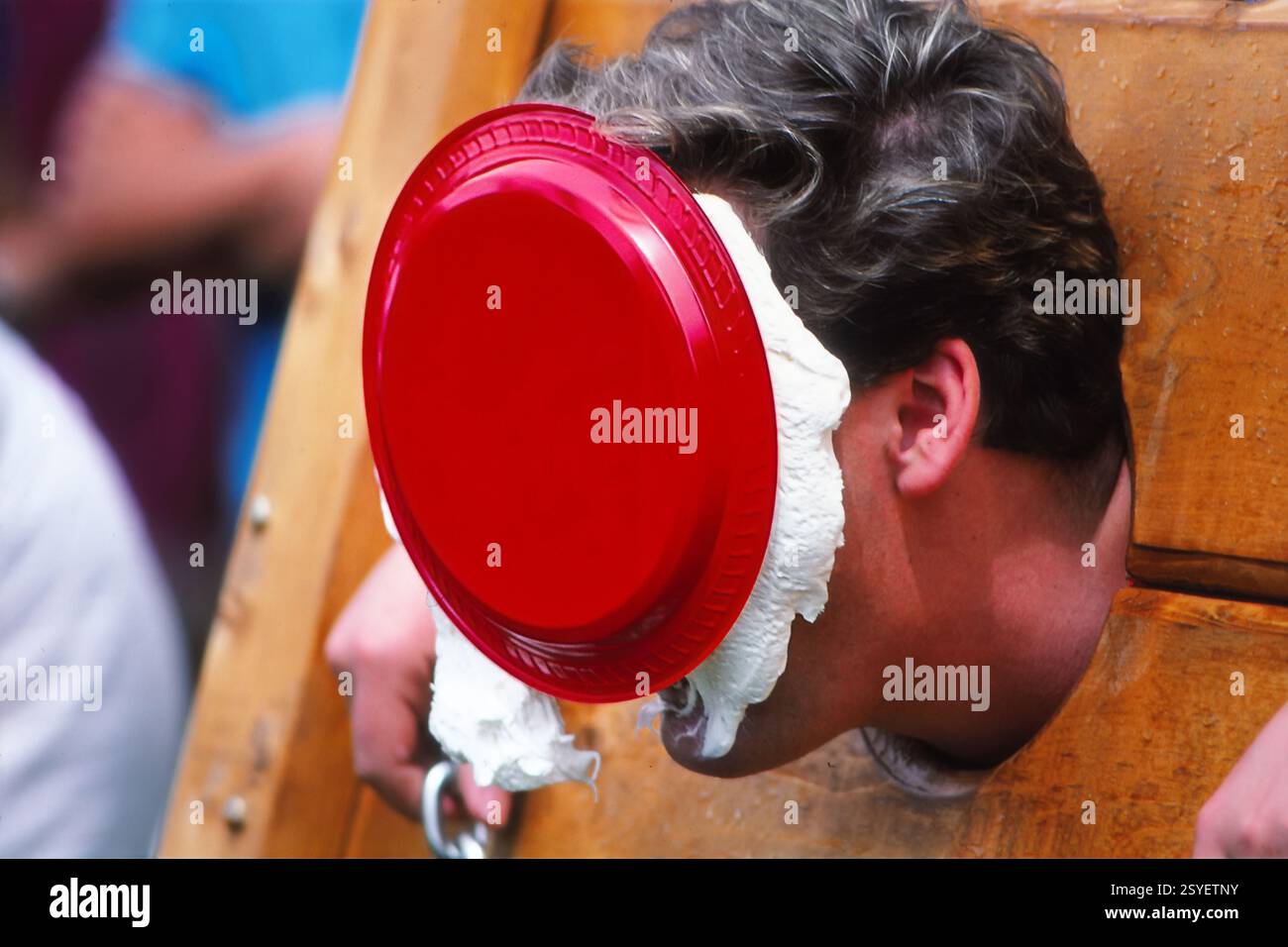 Man at a fun fair amusement getting a pie in the face while being ...