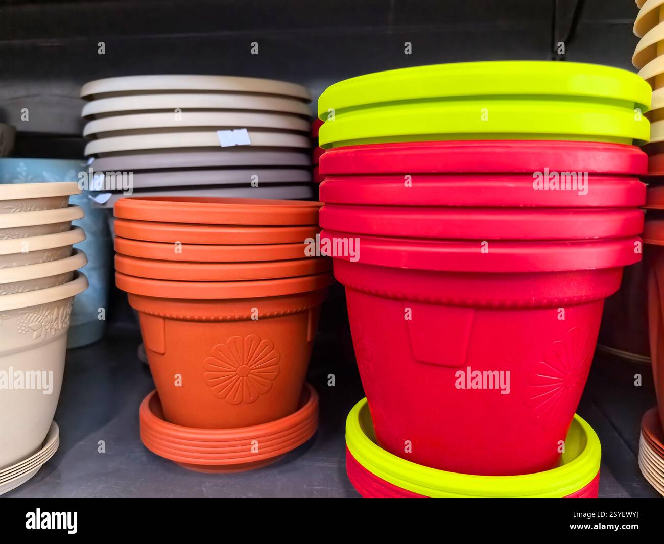 A vibrant collection of flower pots in various colors rests neatly on a ...