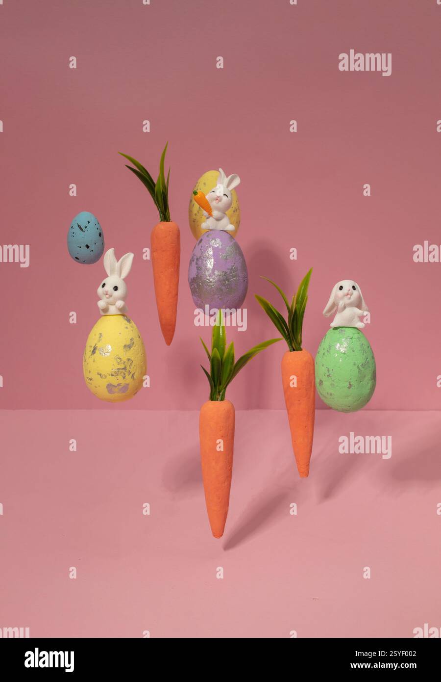 Easter layout made with carrots, eggs and bunnies on pastel pink ...