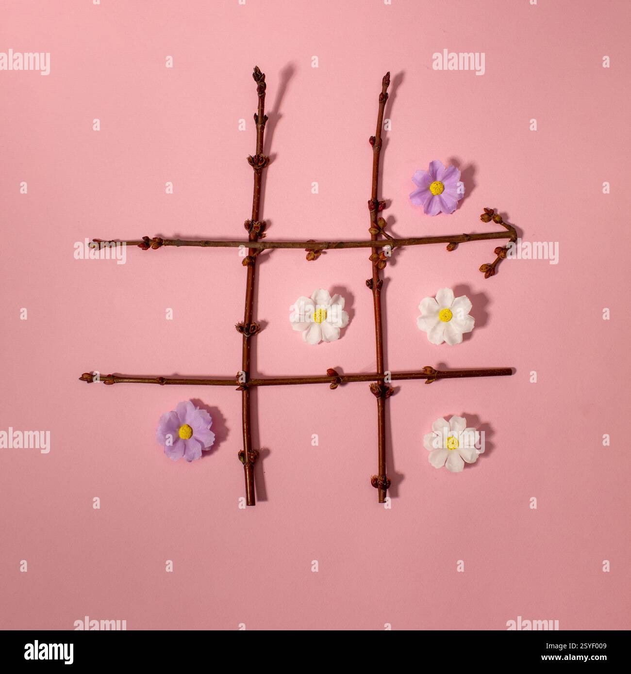 Tic tac toe with Easter elements white and purple flowers. Flat lay ...