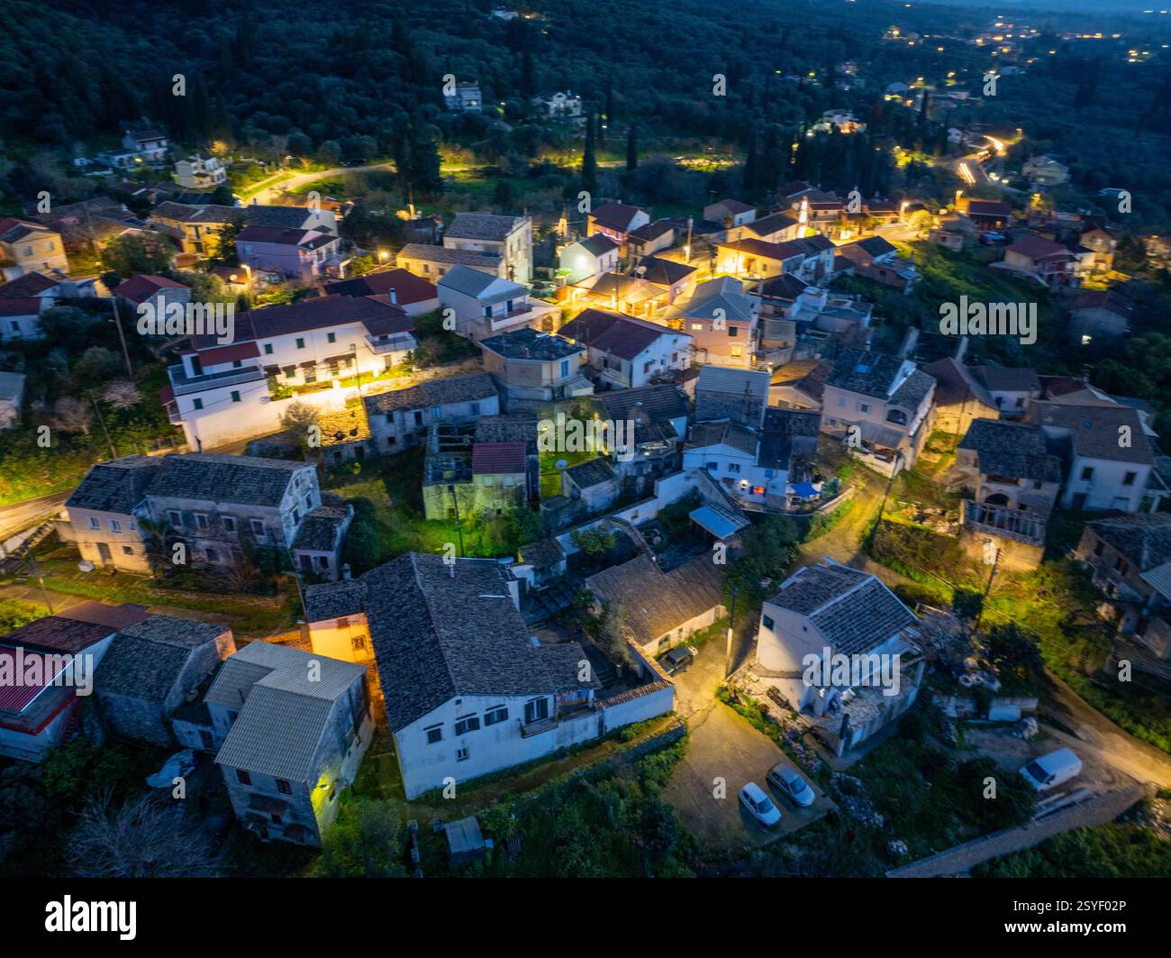 Night aerial view of a hillside town with warm lights illuminating ...