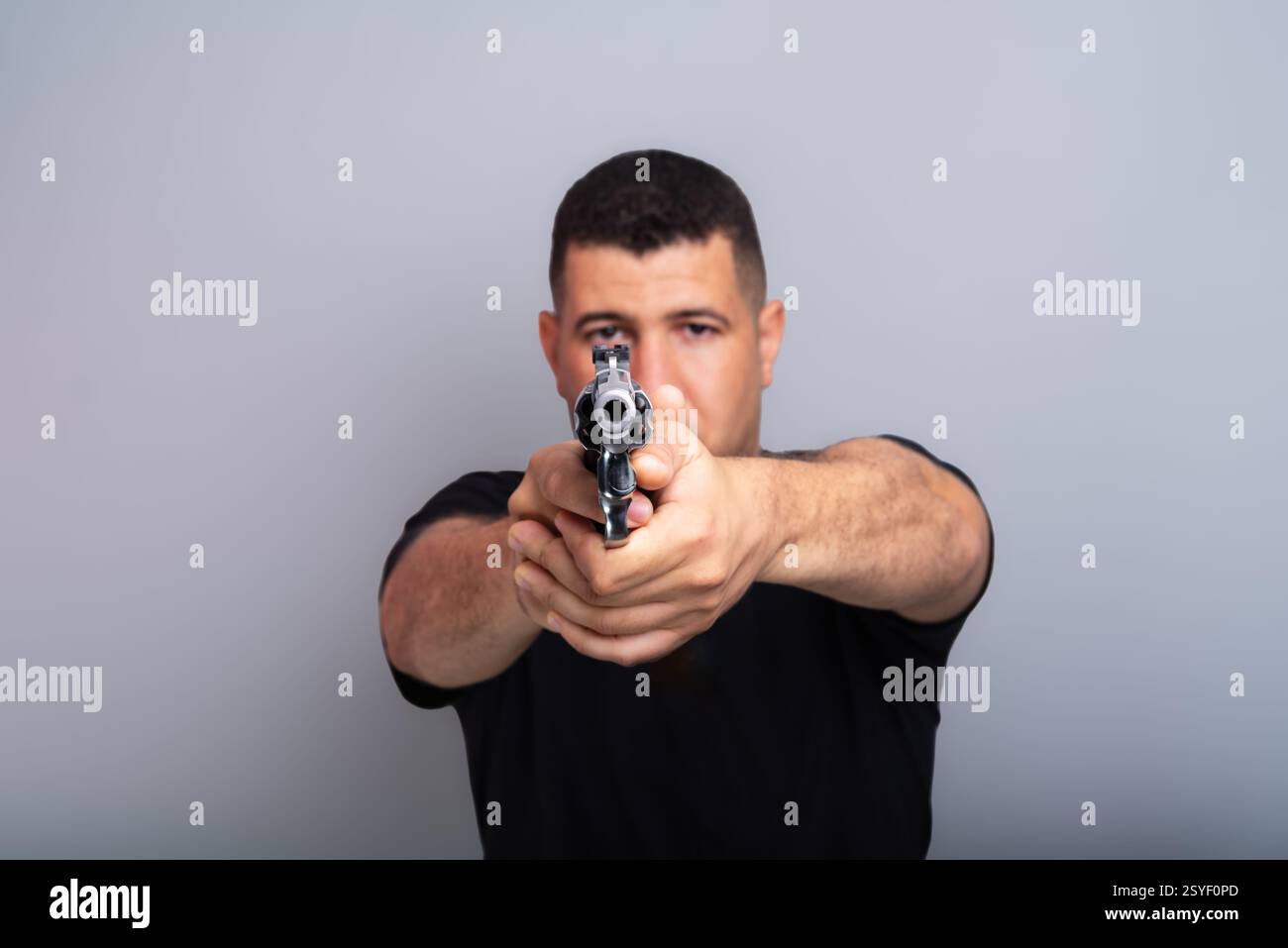 Studio portrait of a shooting instructor pointing a firearm at the ...