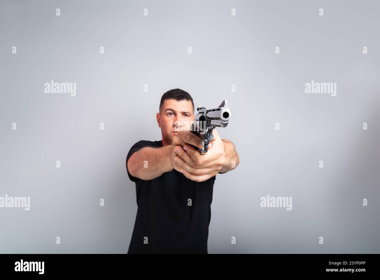 Studio portrait of a shooting instructor pointing a revolver to the ...