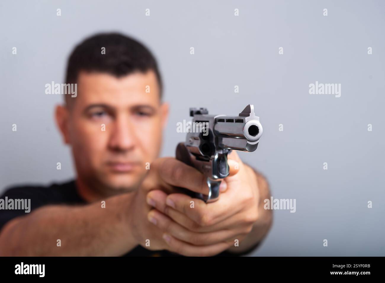 Studio portrait of a shooting instructor pointing a revolver to the ...