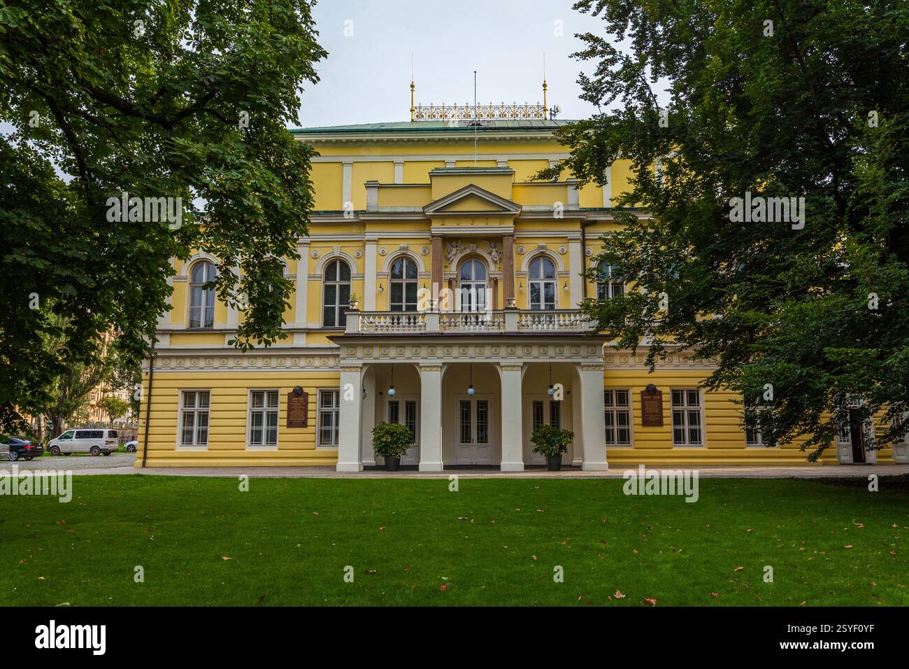 A grand, symmetrical building with a pale yellow facade, featuring a ...