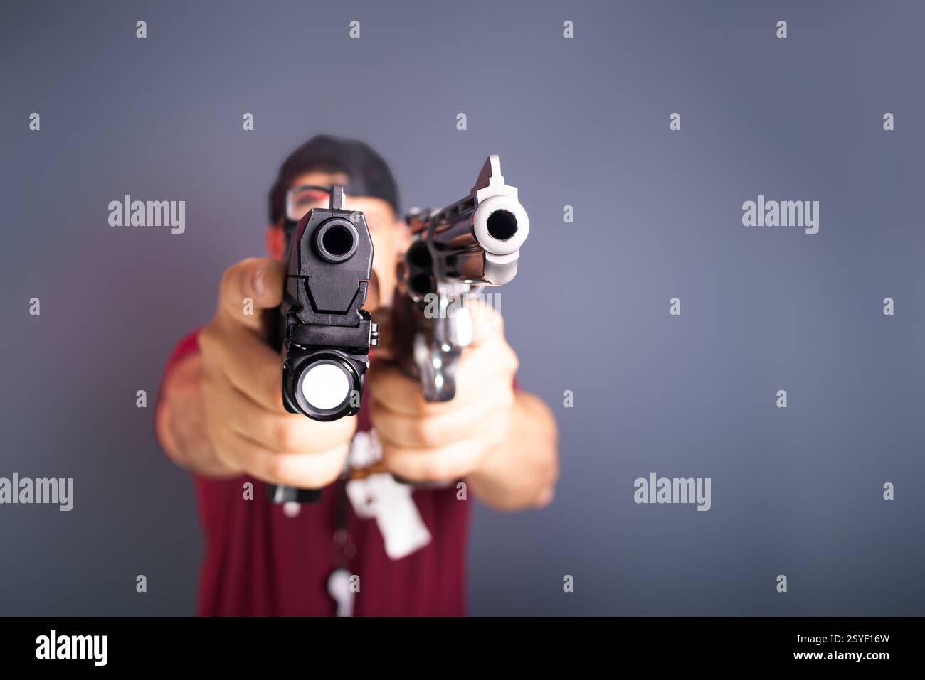 Studio portrait of a shooting instructor wearing a hat pointing two ...