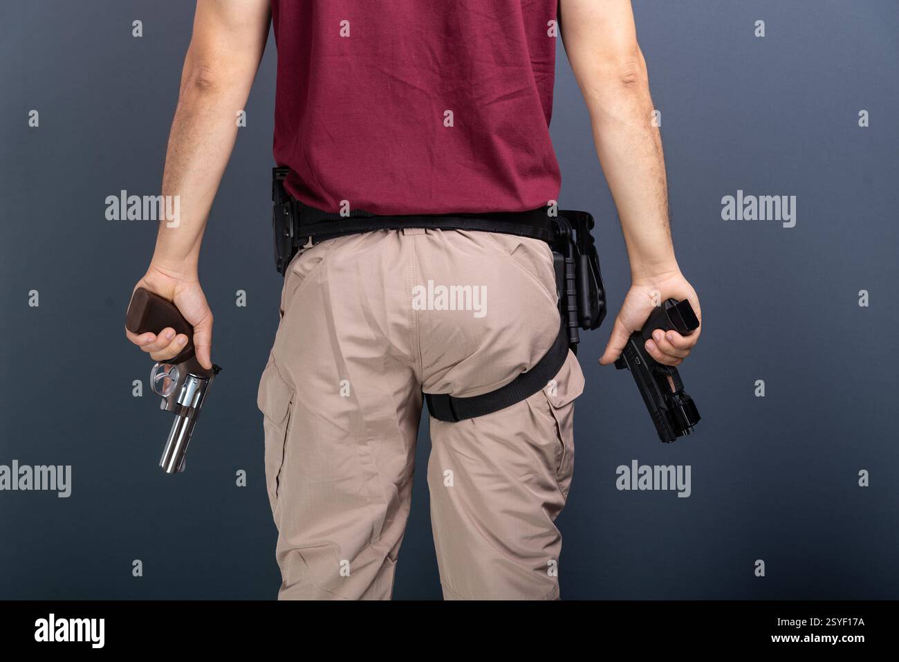 Shooting instructor, with his back to the camera, holding two guns ...