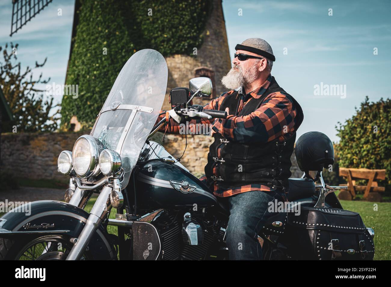 Kultiger Rocker mit einer klassischen Harley-Davidson vor einer alten ...
