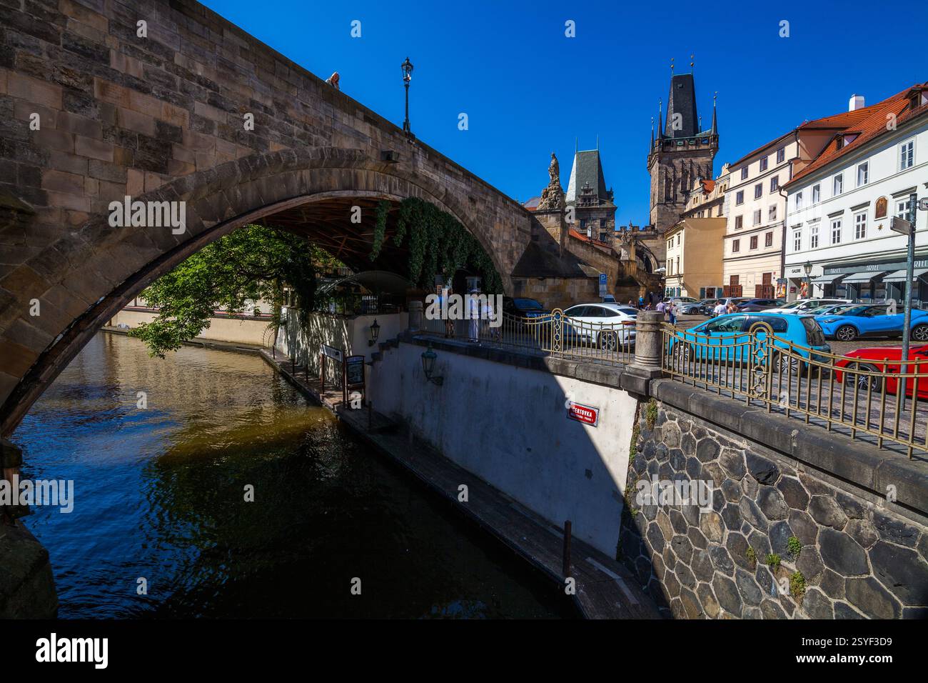 A stone bridge arching over a narrow river with buildings lining the ...