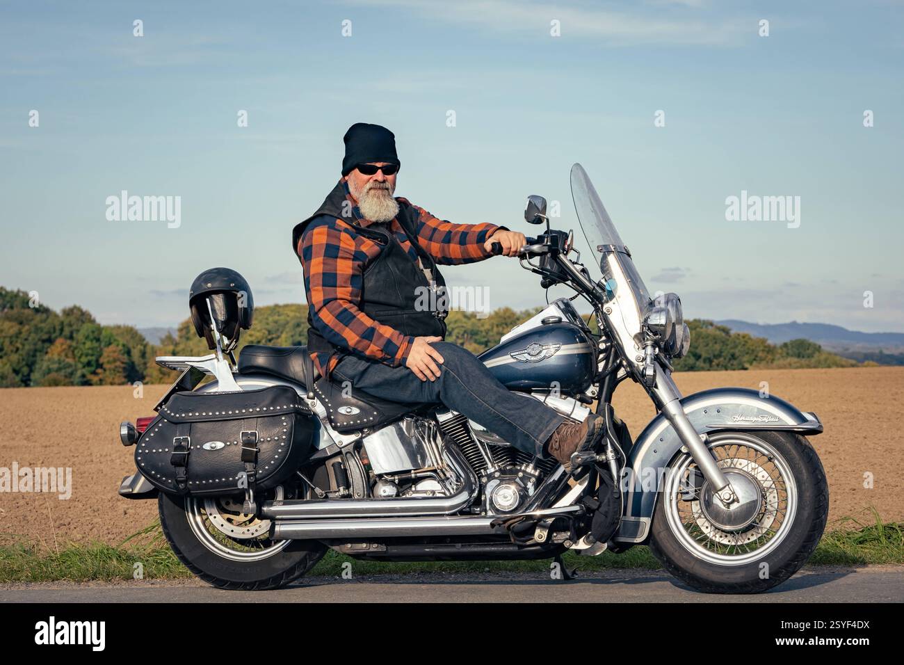 Stolzer Biker mit seiner kultigen Harley-Davidson possiert auf einer ...