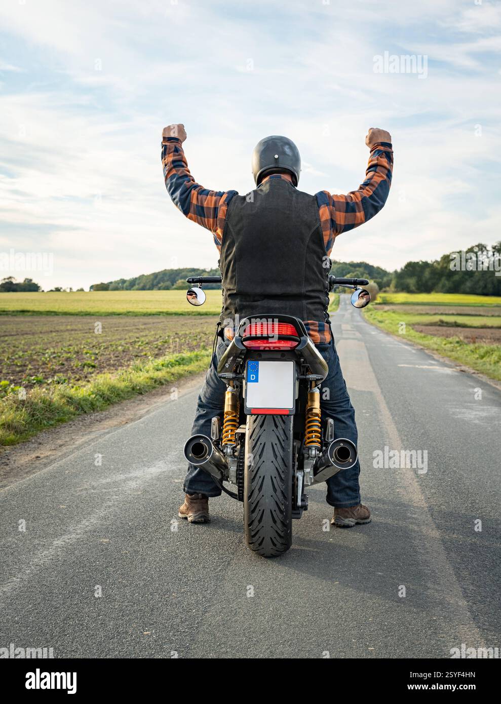 Motorradfahrer auf seiner Maschine von hinten in Siegerpose ...