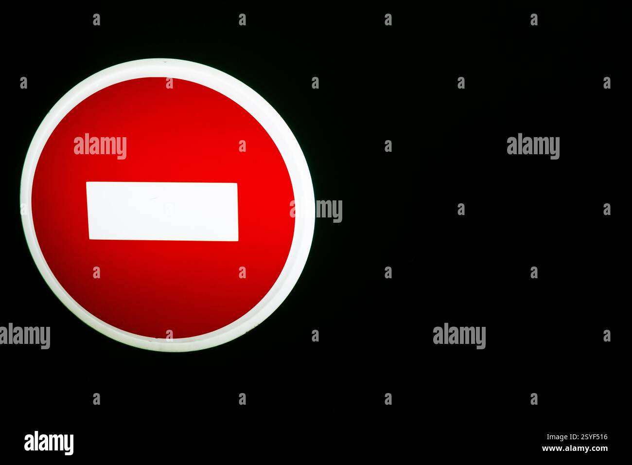 A bright red circular sign with a white horizontal bar is illuminated ...