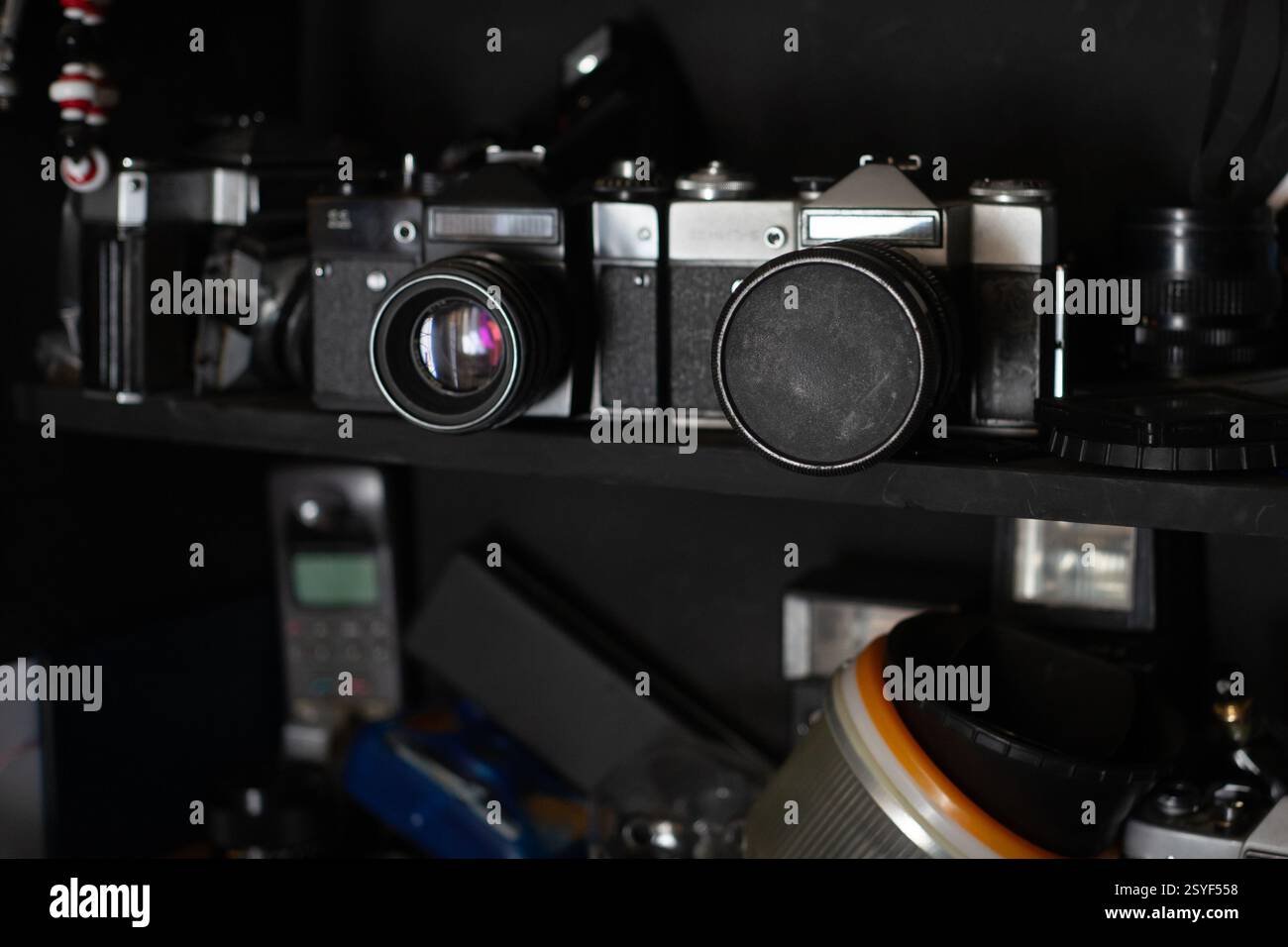 A collection of vintage cameras is neatly arranged on a shelf. Various ...