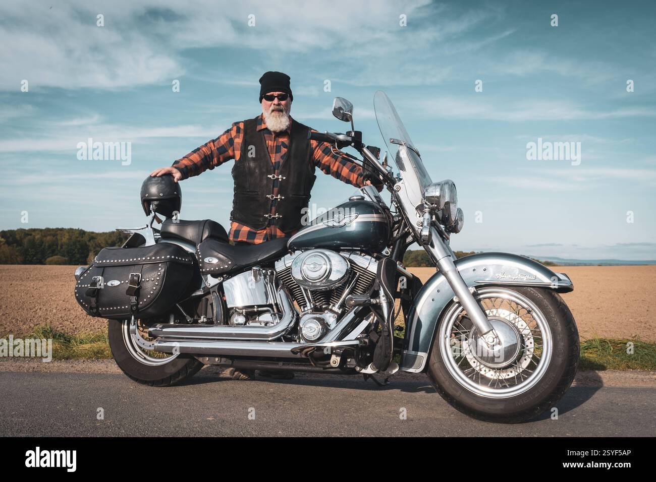 Biker mit kultiger Harley-Davidson possiert auf einer Landstraße, Retro ...