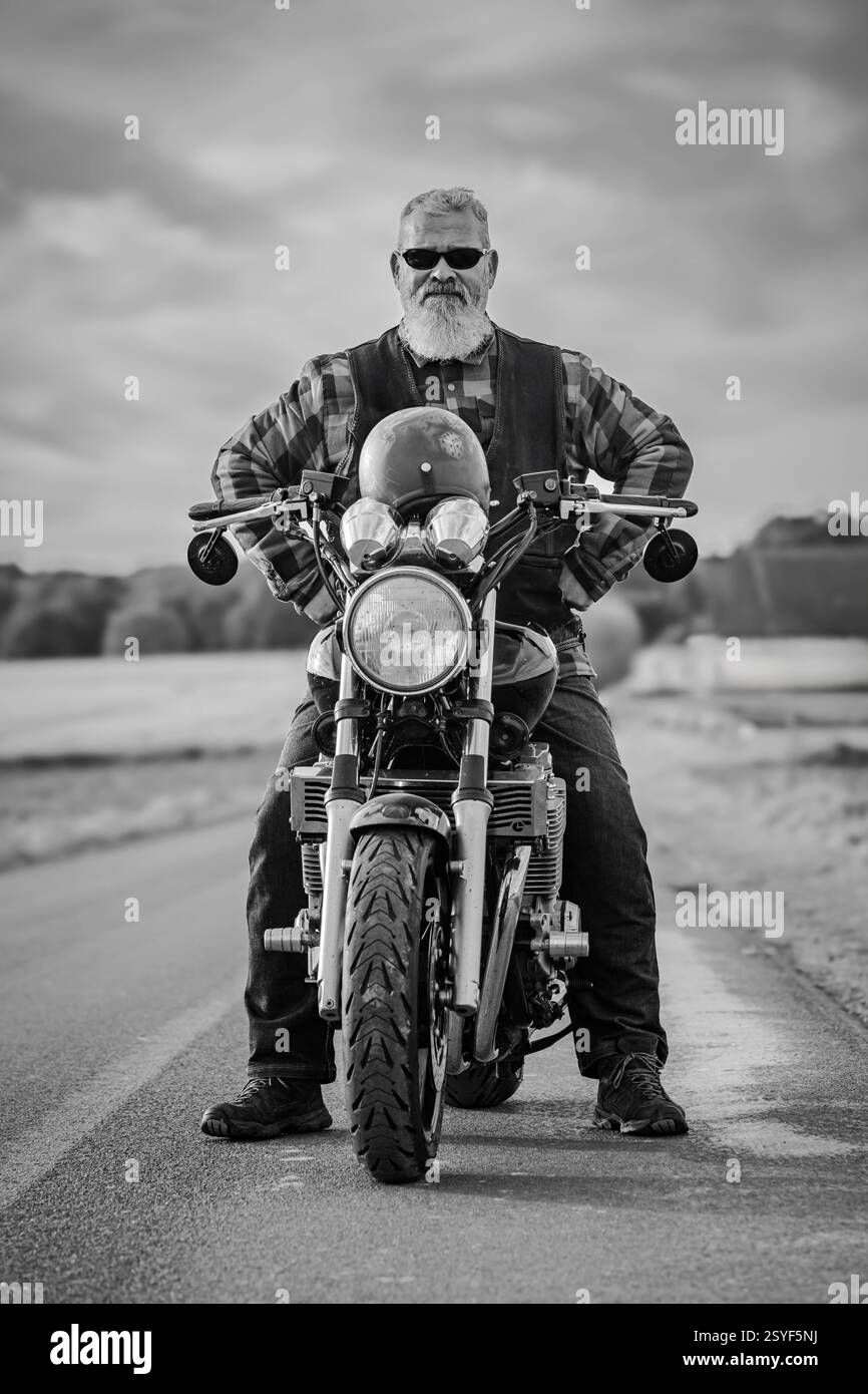 Cooler Motorradfahrer mit Sonnenbrille und weißem Bart sitzt stolz auf ...