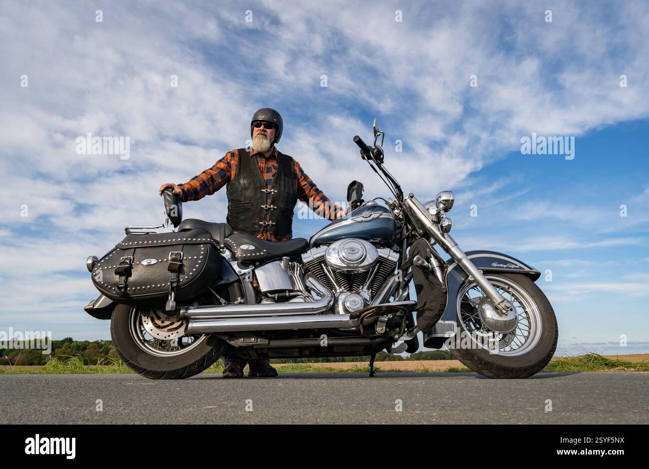Kultiger Rocker mit seiner Harley-Davidson fährt auf einer Landstrasse ...