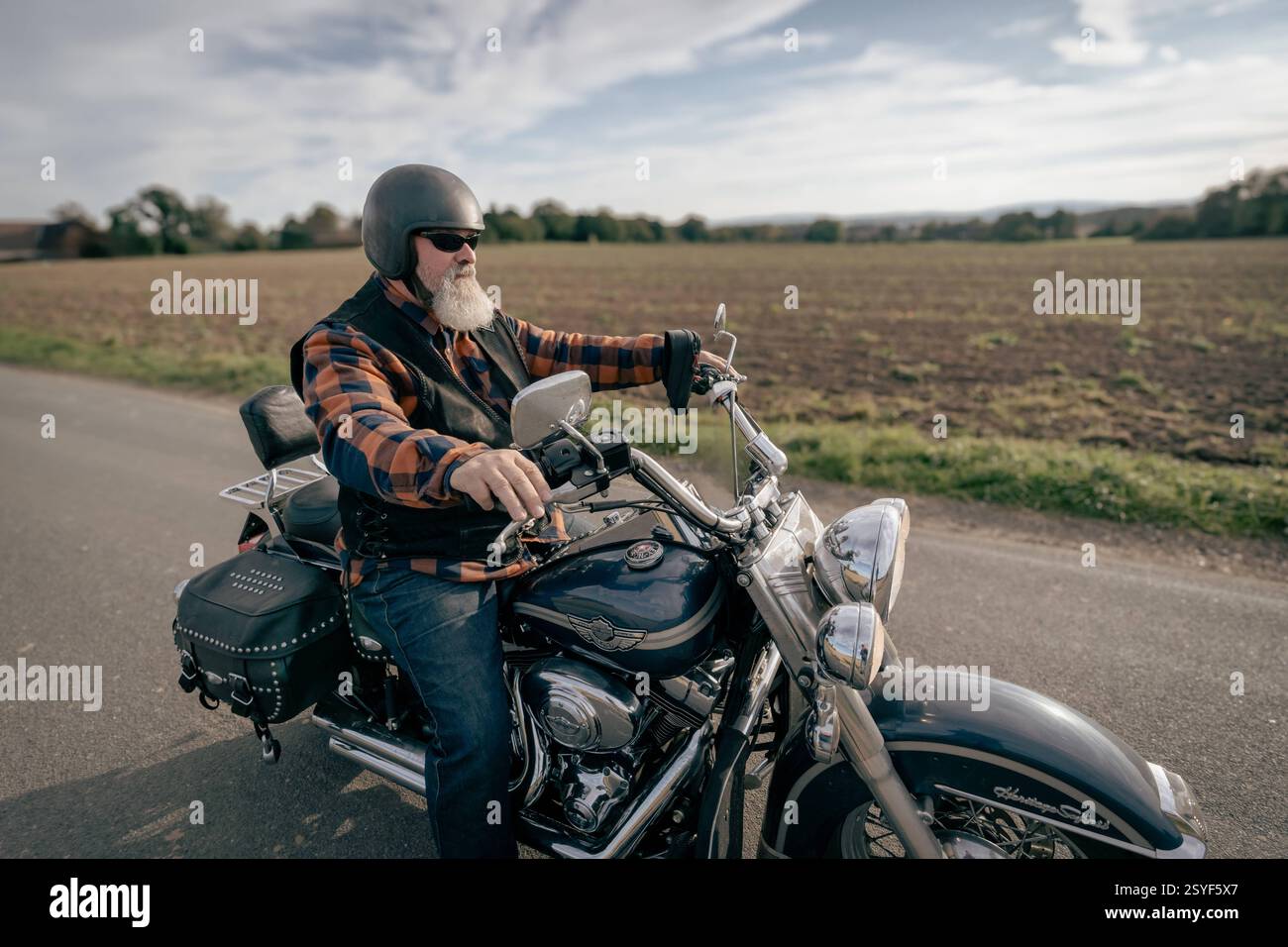 Kultiger Rocker mit seiner Harley-Davidson fährt auf einer Landstrasse ...