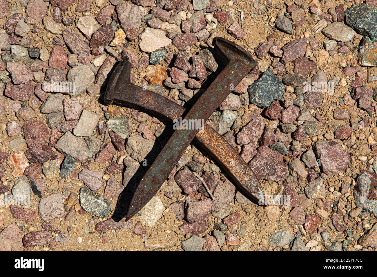 A crossed pair of old railroad spikes lie on the ground near railroad ...