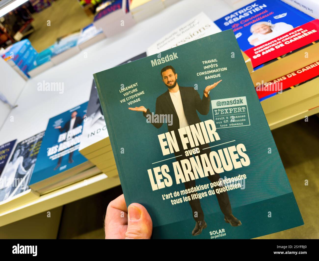Paris, France - Feb 18, 2025: A person holds En Finir avec les Arnaques ...