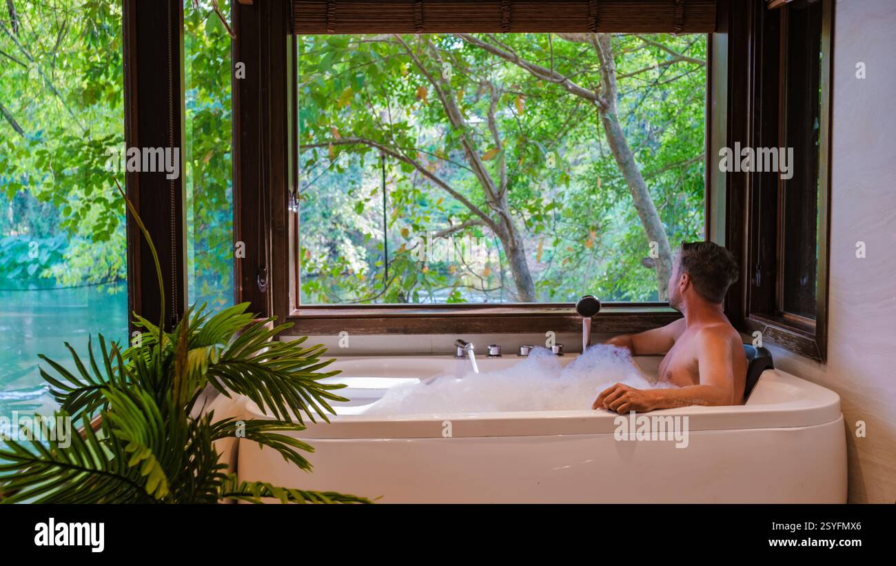 Enjoying a serene moment, a man soaks in a bathtub surrounded by lush ...
