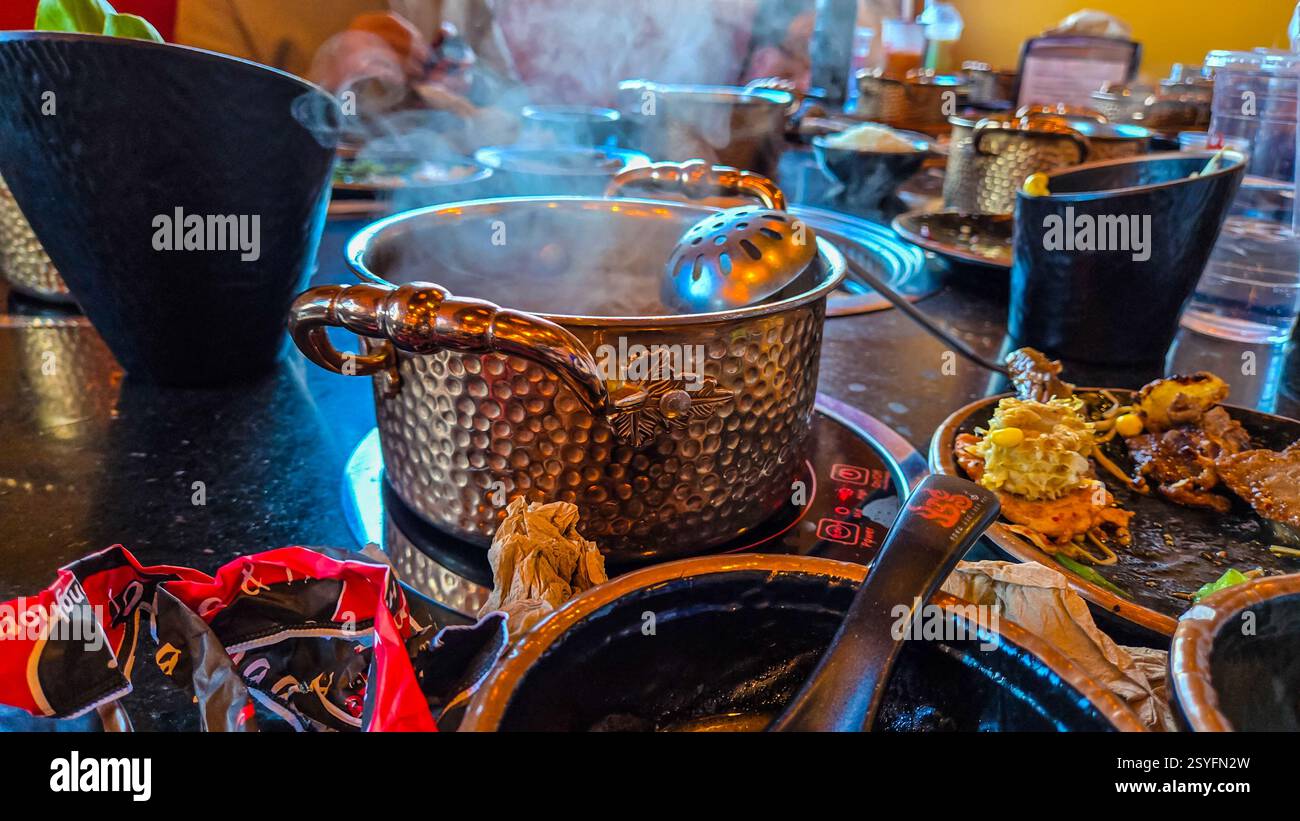 Guests enjoy a communal hotpot meal with boiling broth and fresh ...