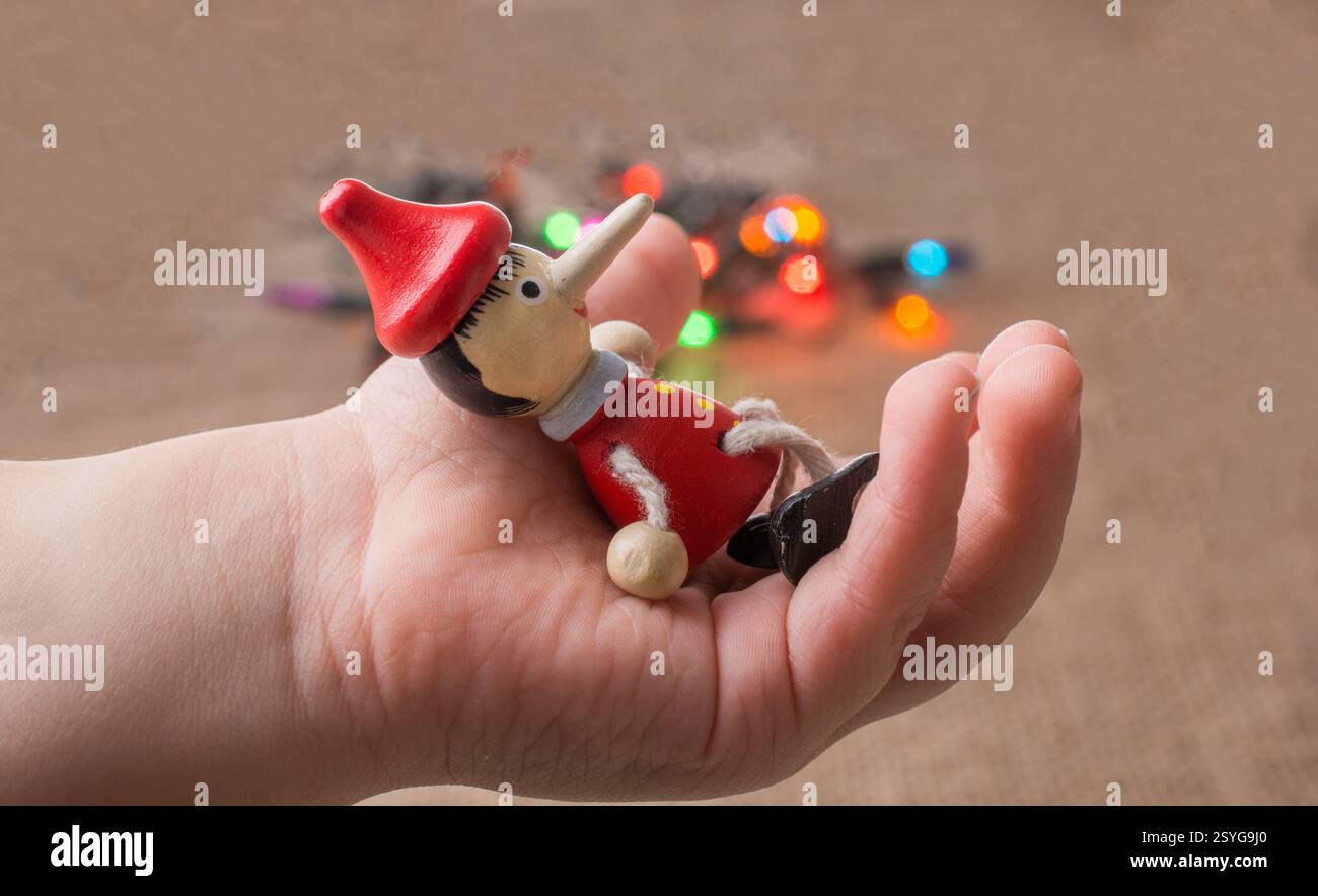 Wooden Pinocchio doll sitting in hand before lights Stock Photo - Alamy