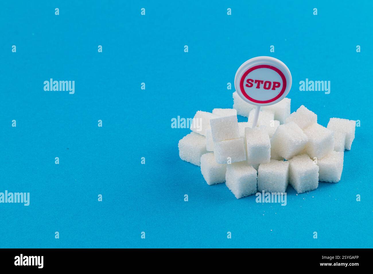 A small mound of sugar cubes is arranged on a bright blue surface ...