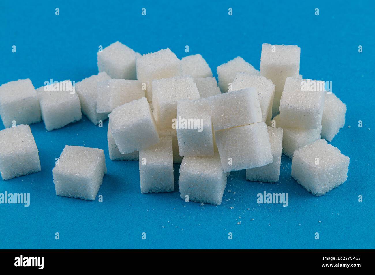 A collection of white sugar cubes is arranged in a scattered manner on ...