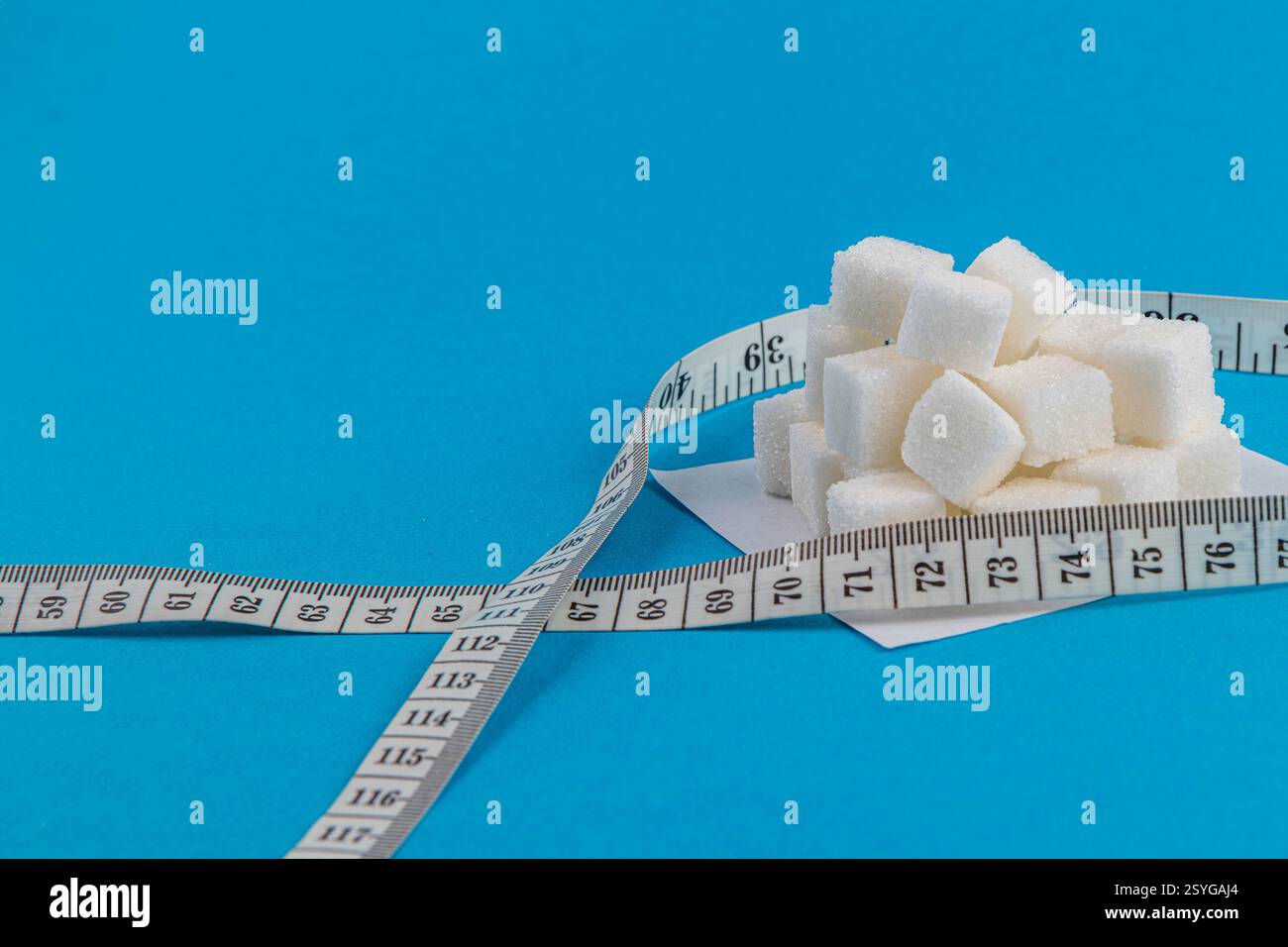 A pile of white sugar cubes sits on a white surface, surrounded by a ...