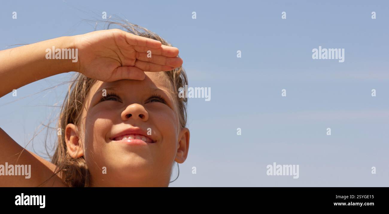 Beautiful caucasian child of 7-8 years looking at sun and covering face ...