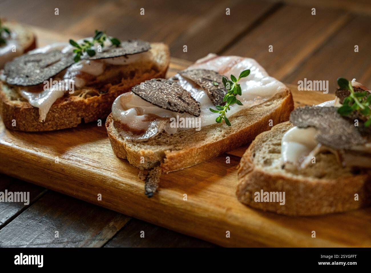 Gourmet bruschetta topped with artisanal lard, thin slices of black ...