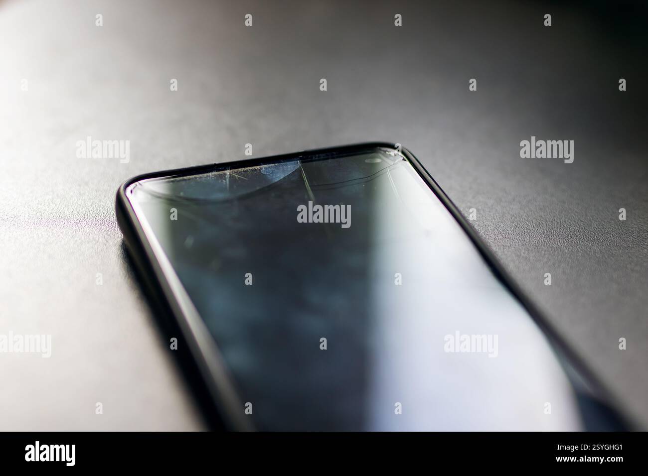 On a table, there is a phone that has a broken screen, showcasing its ...
