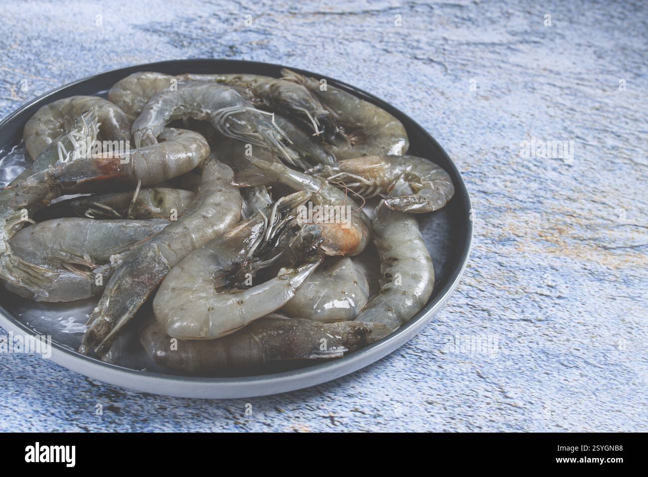 Fresh shrimp, laid out on a round plate, on a blue background, ready ...