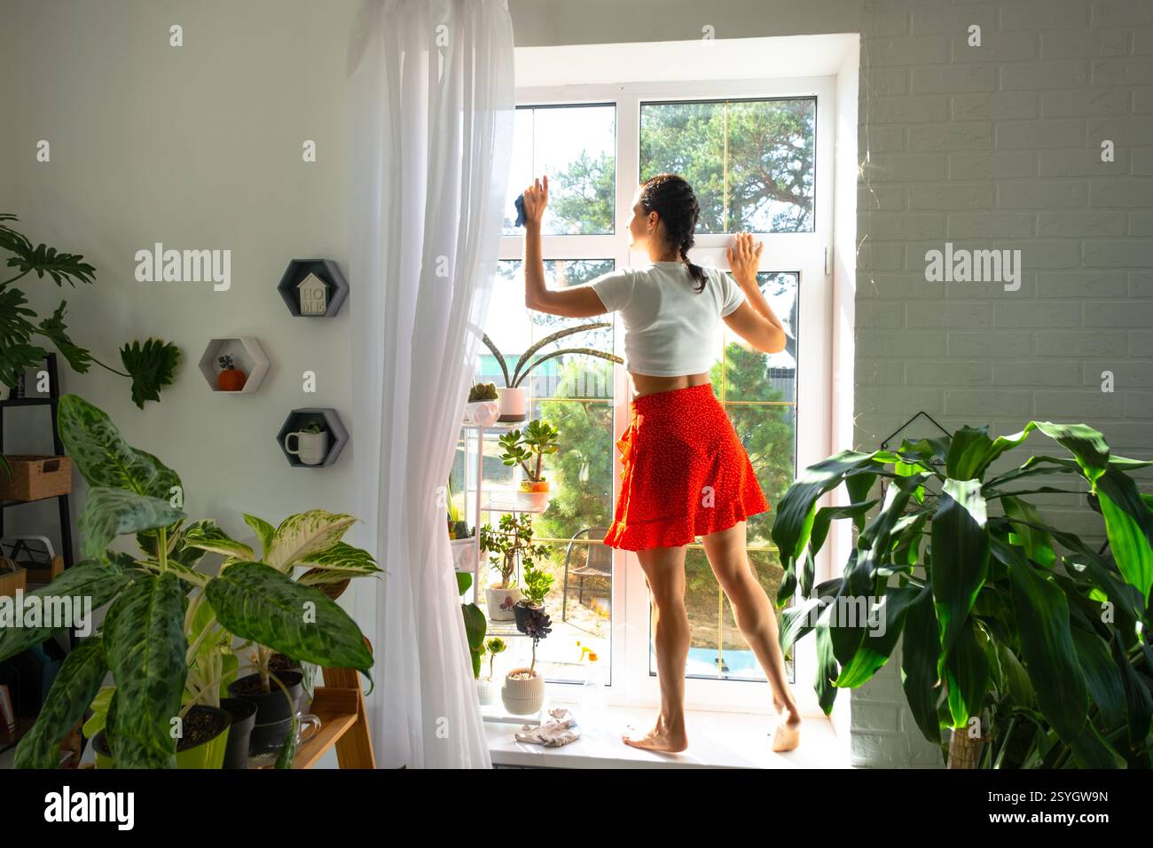 Woman manually washes the window of house with rag cleaner and mop inside the interior with home ...