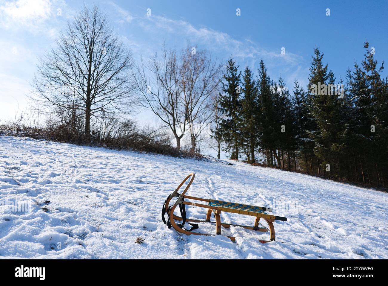 Wooden retro sled positioned on a snowy slope under a blue sky with ...
