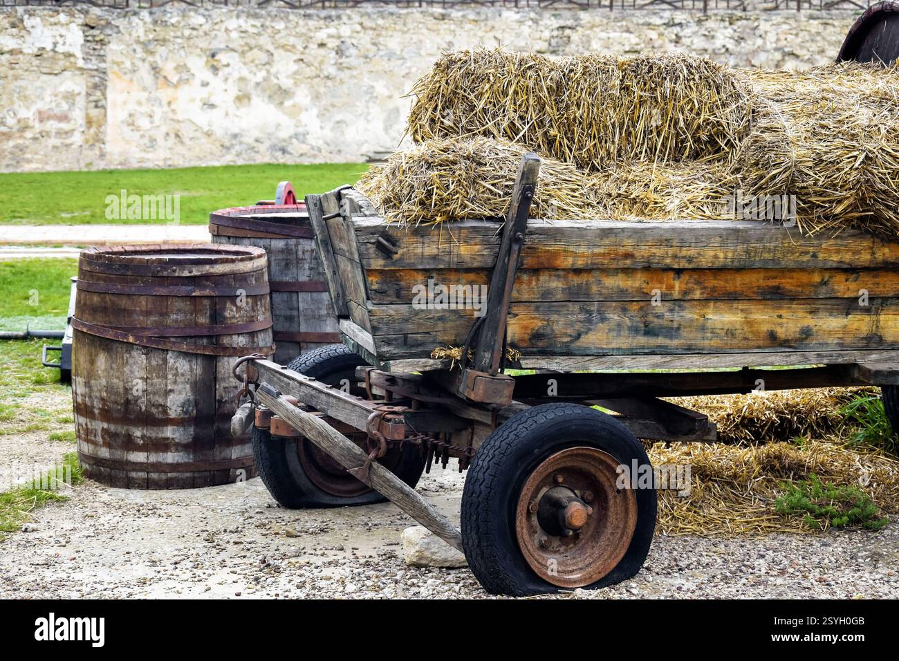 Old wooden cart with bales of hay, wine barrels against background of ...