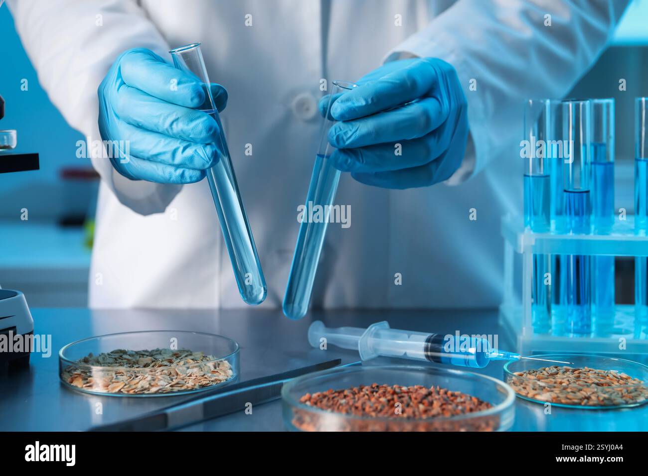 GMO concept. Scientist holding test tubes of liquid at table with ...