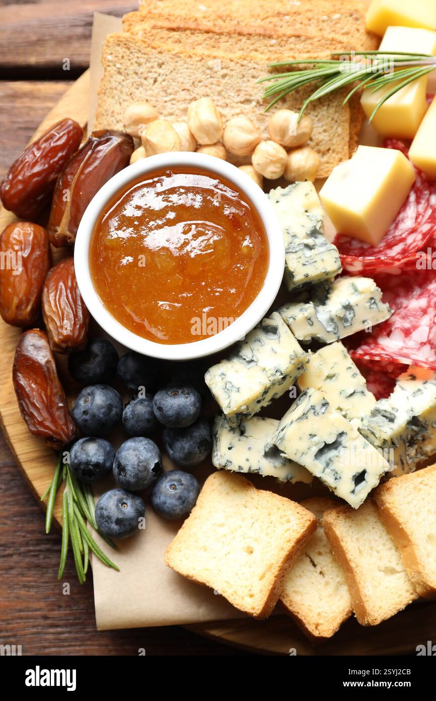 Different types of delicious cheese and other snacks on wooden table ...