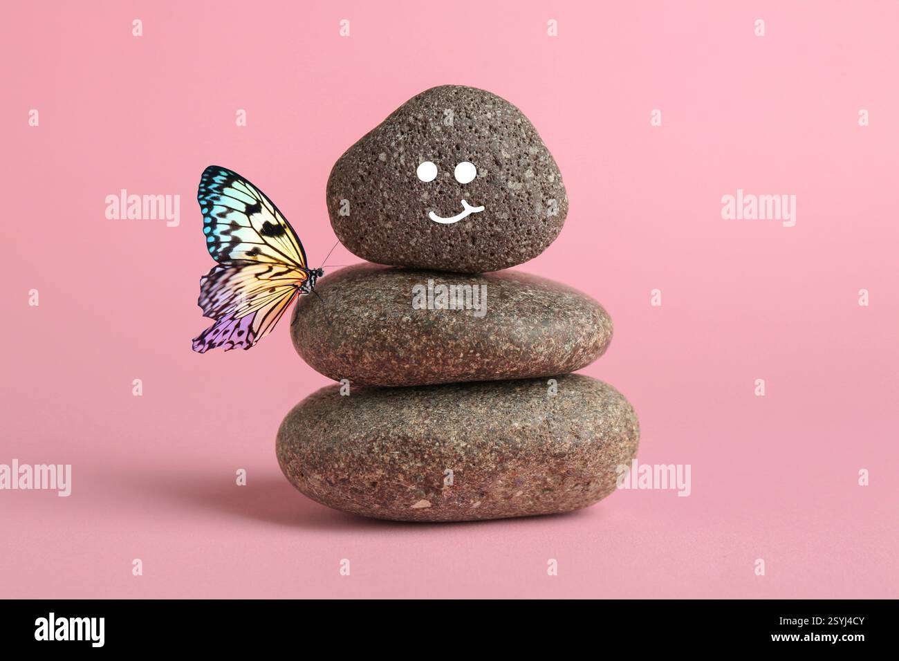 Happy stone glad to see butterfly, harmony. Stacked pebbles and one with smiling face on top ...