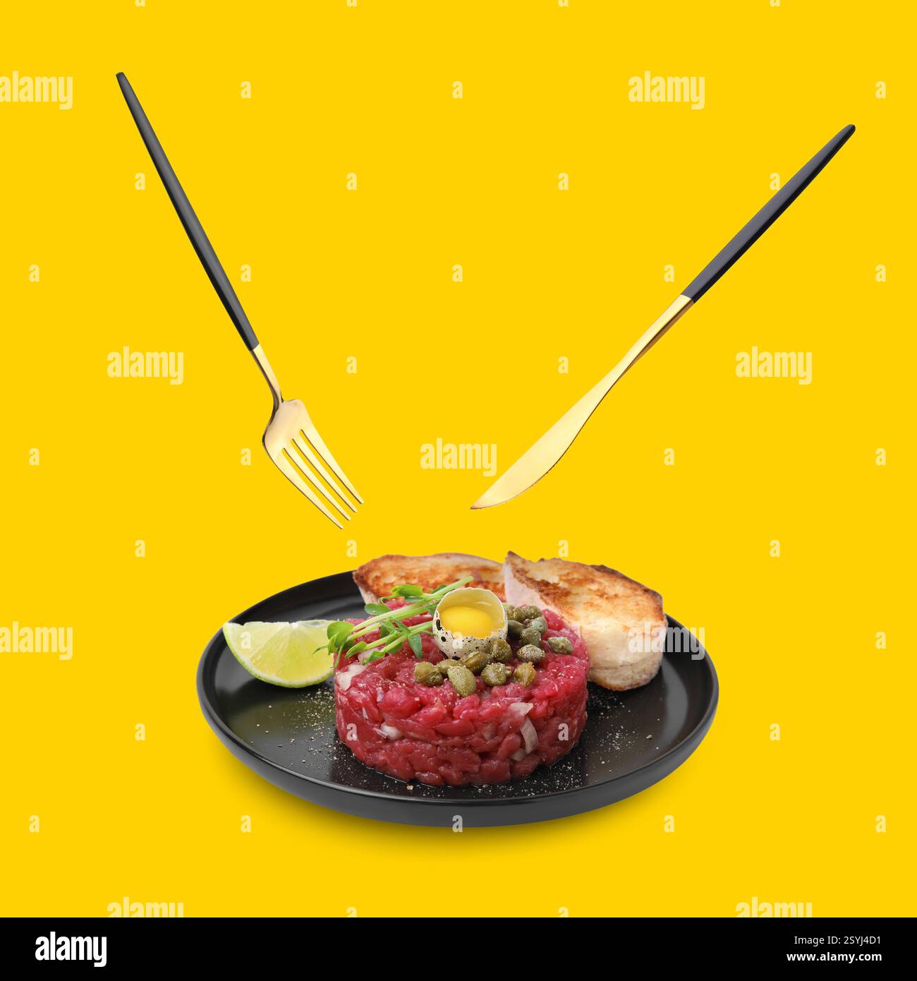 Cutlery in air over plate with tasty beef steak tartare on golden ...