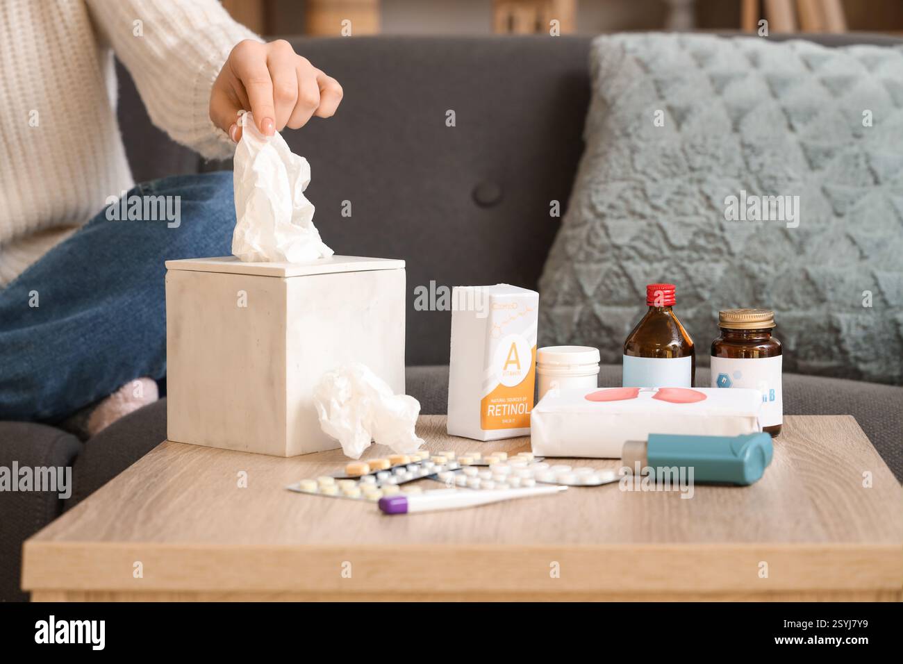 Woman taking tissues from box on table with medicines in room. Closeup ...
