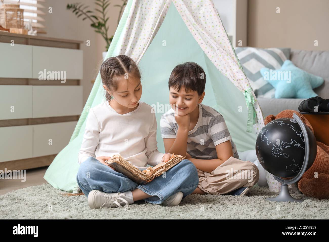 Cute children reading adventure book at home Stock Photo - Alamy